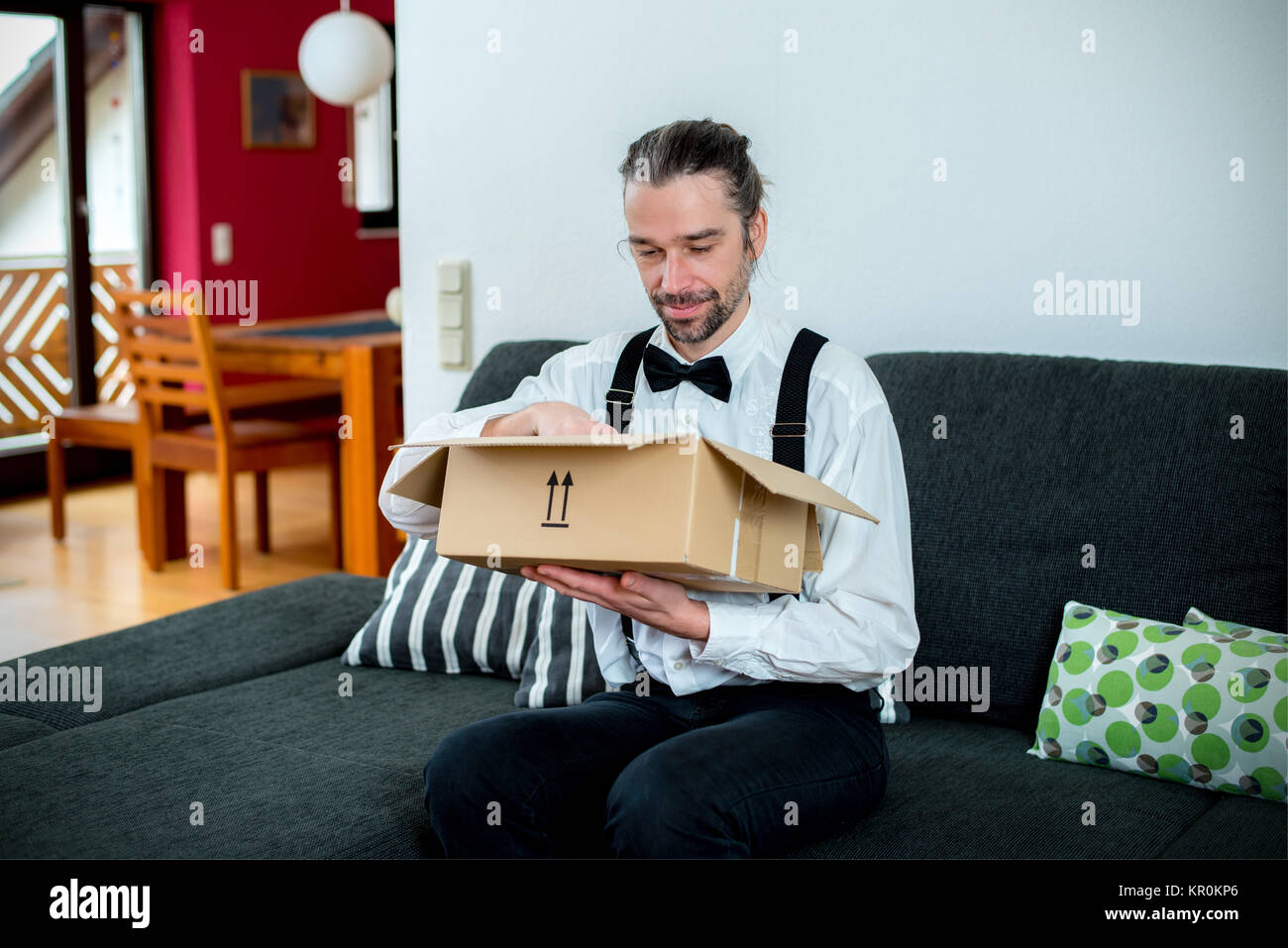 young bearded man in white shirt with bow-tie opening a package Stock ...