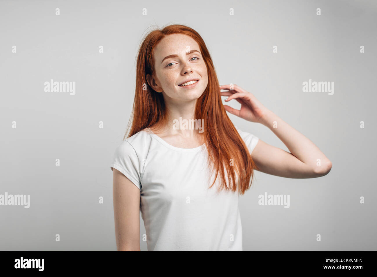 girl smiling with closed eyes touching her red hair over white background Stock Photo - Alamy