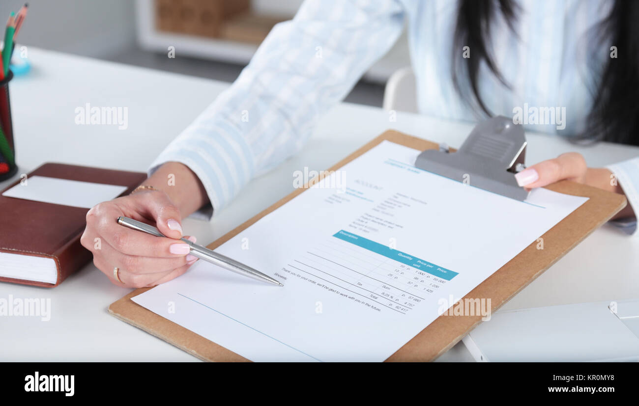 Business women sitting on desk and writing a paper Stock Photo - Alamy