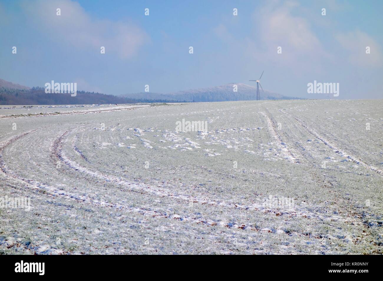 frozen field on a cold clear winter and a windmill in the background ...