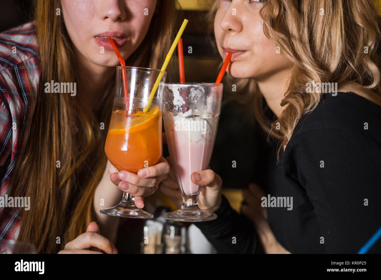 Young woman drinking milkshake while sitting with friends at cafe Stock ...
