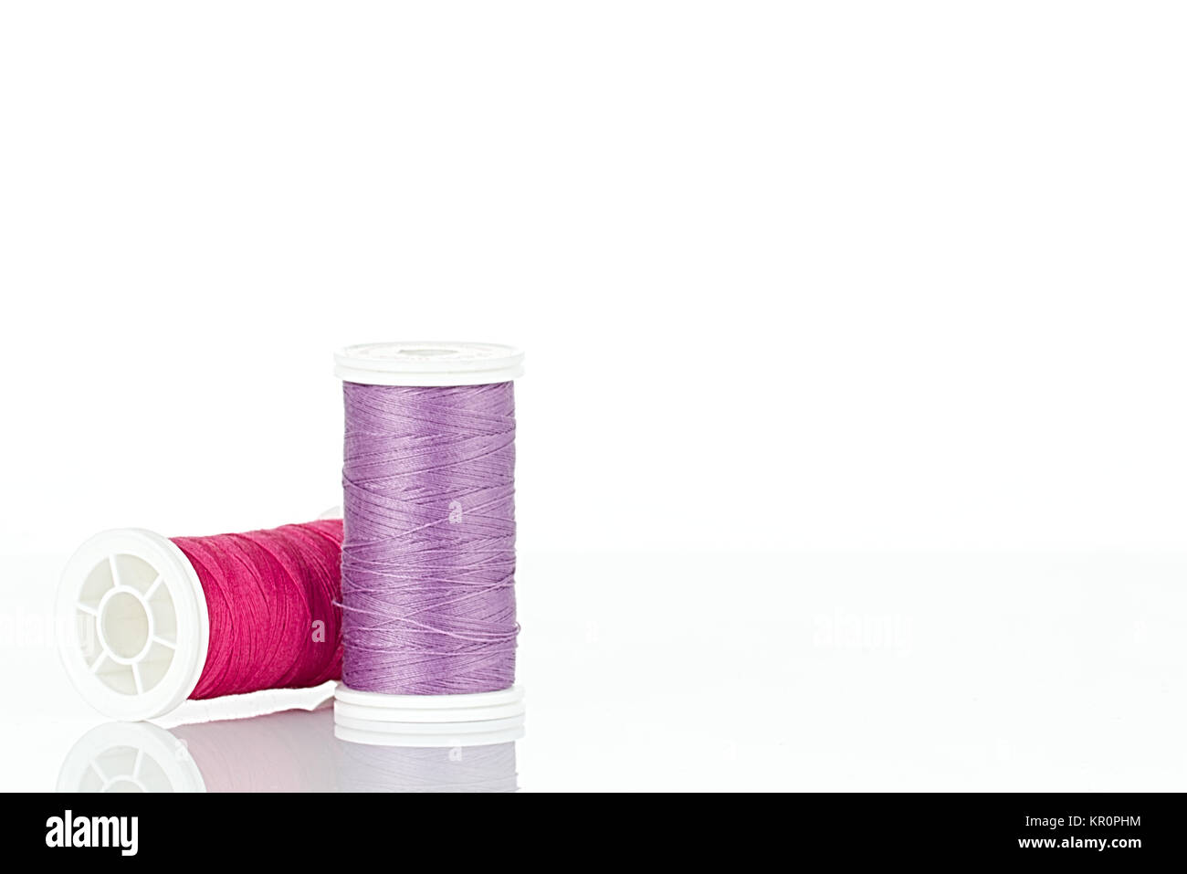 Cotton reels in shades of purple and pink isolated on a white ...