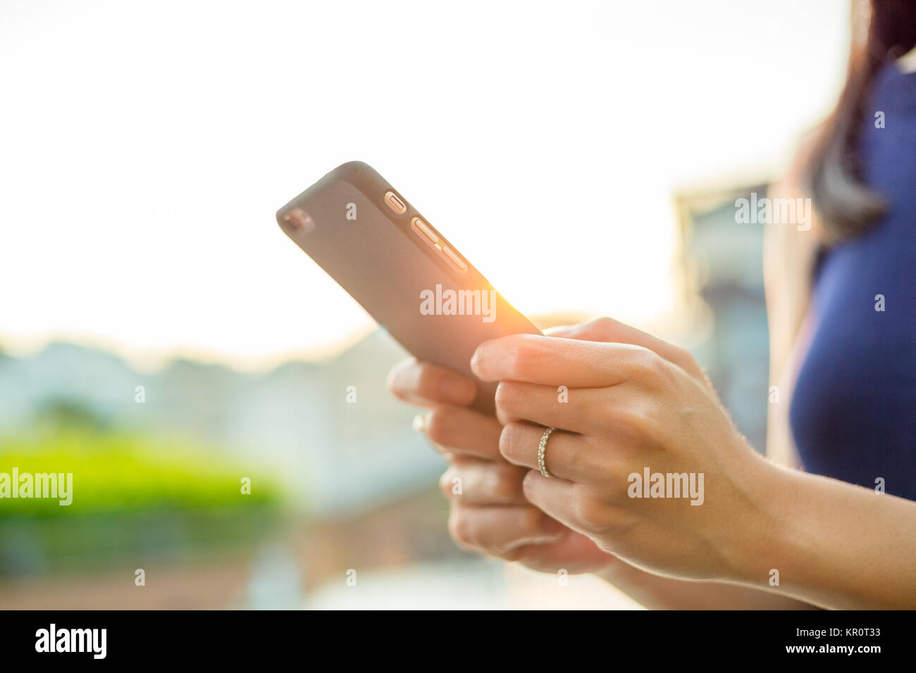 Woman using mobile phone under sun flare Stock Photo - Alamy