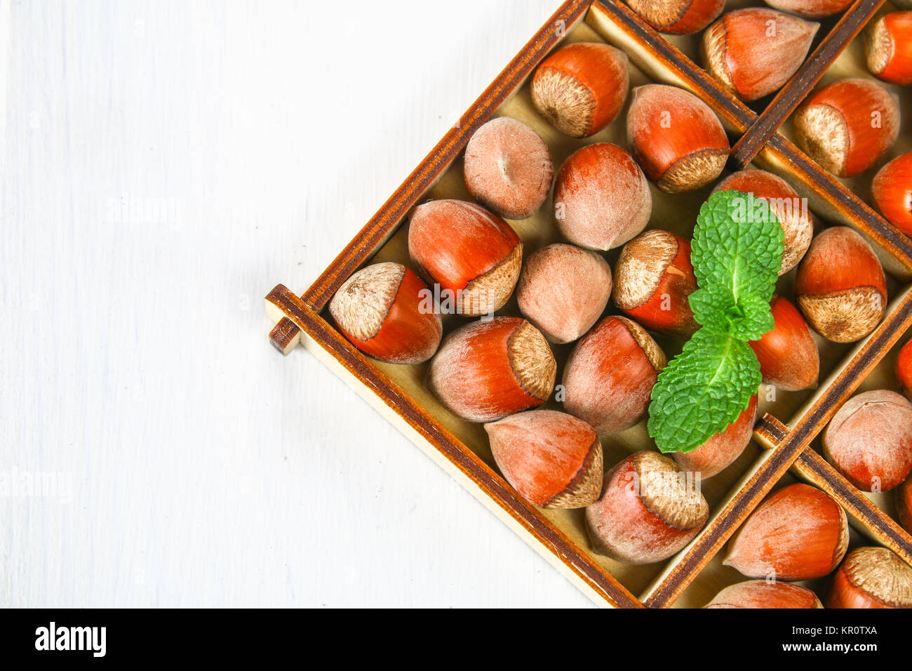 Walnut hazelnuts in a square wooden box with dividers on a white wooden ...