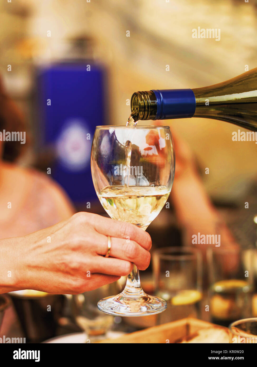 Pouring White Wine into a Glass Held by a Hand in Close Up Against a ...