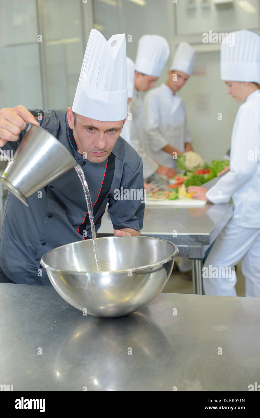 Chef pouring liquid into stainless steel bowl Stock Photo - Alamy