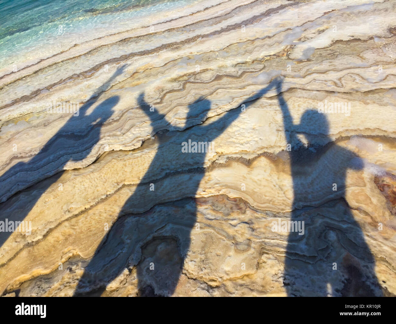 shadows of three happy people at beach raising hands Stock Photo - Alamy