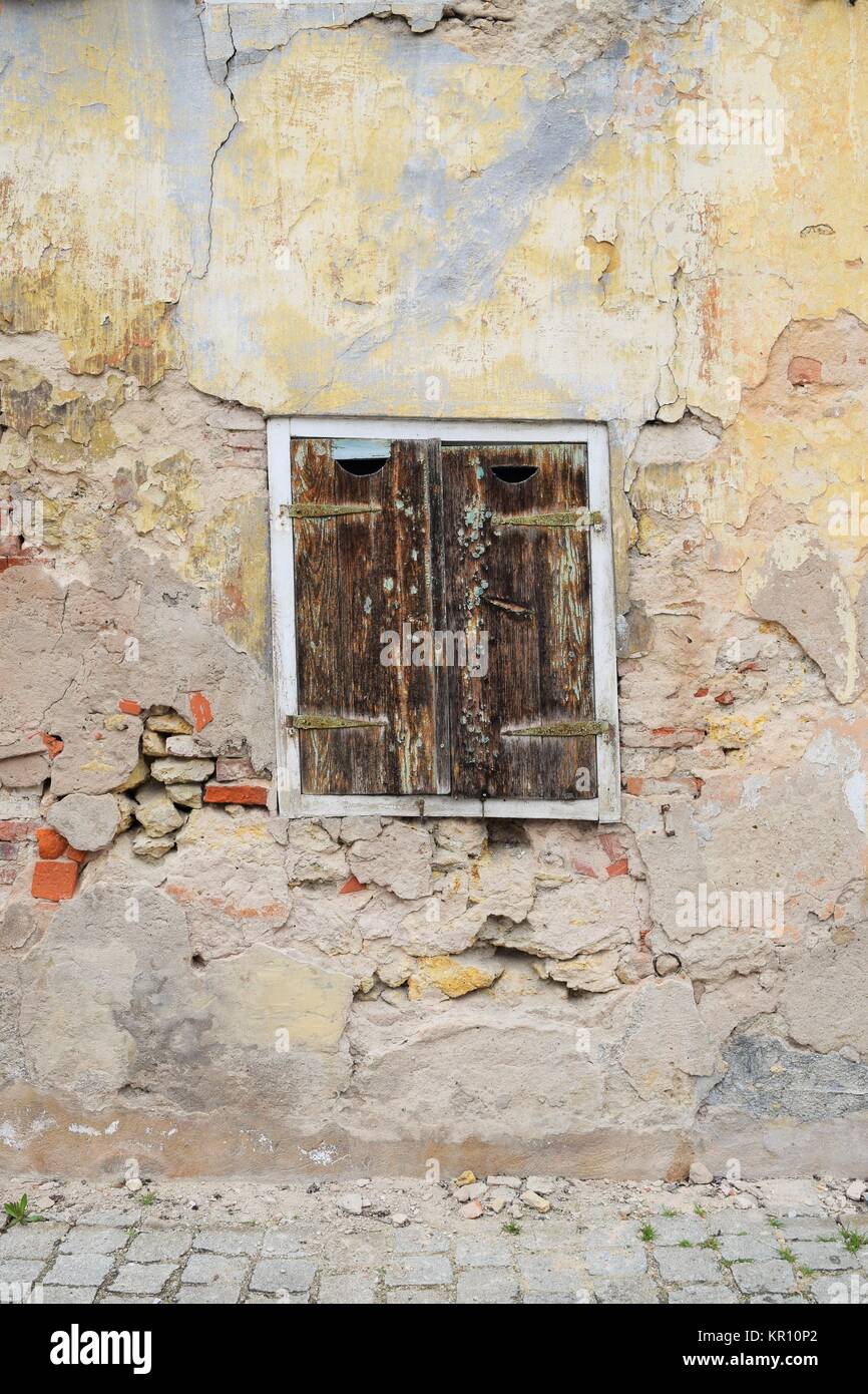 old wooden window with closed shutters in a dilapidated house in need ...