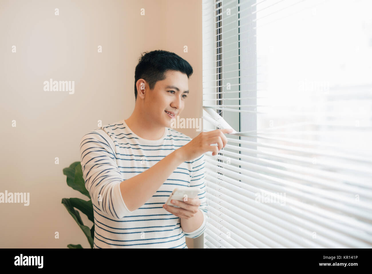 Young asian man standing by the window in the morning Stock Photo - Alamy