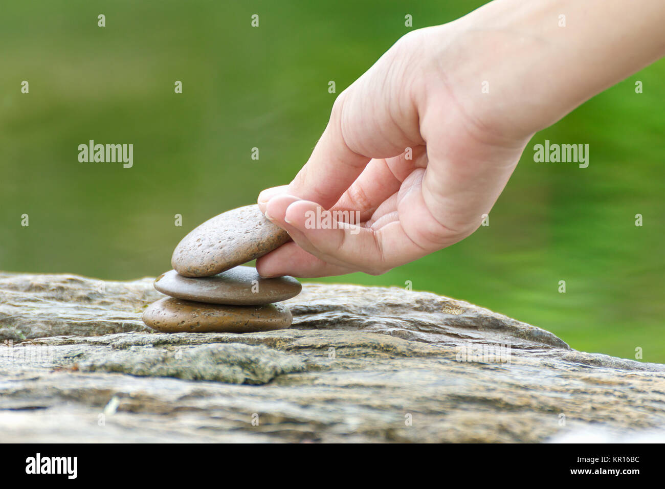Hand put stone building a pile of zen stones Stock Photo - Alamy