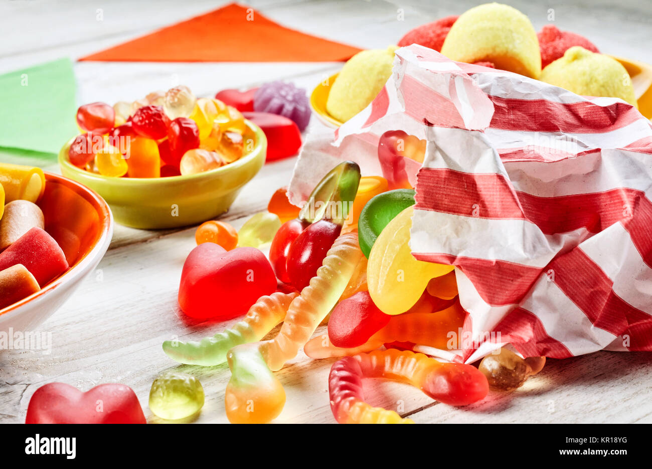 Close up view of stripped bag filled with candy besides bowl of gummy ...