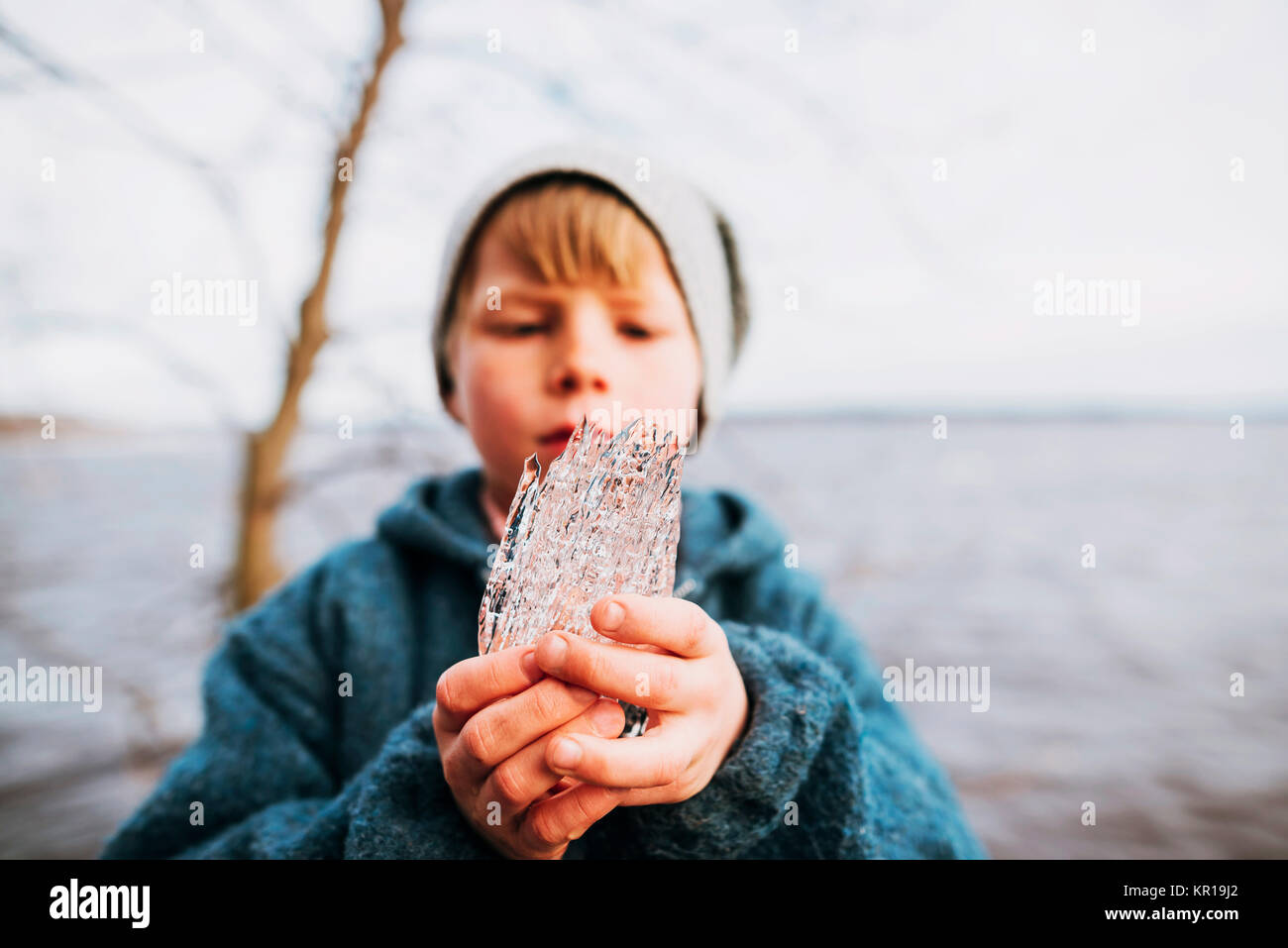 Boy standing by a lake holding a piece of ice Stock Photo - Alamy