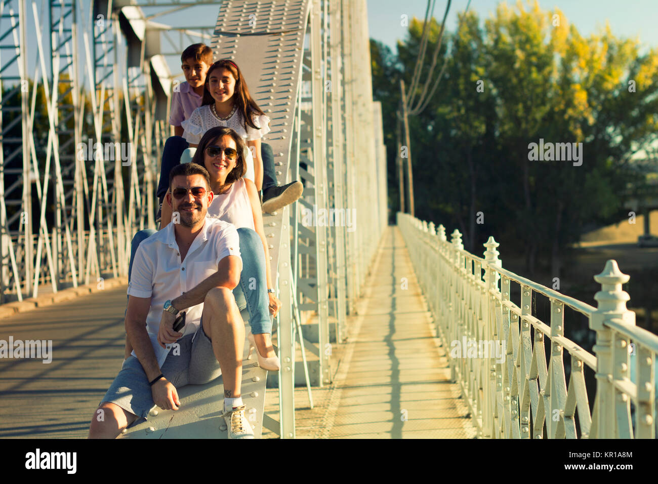 Family sitting on a bridge Stock Photo - Alamy