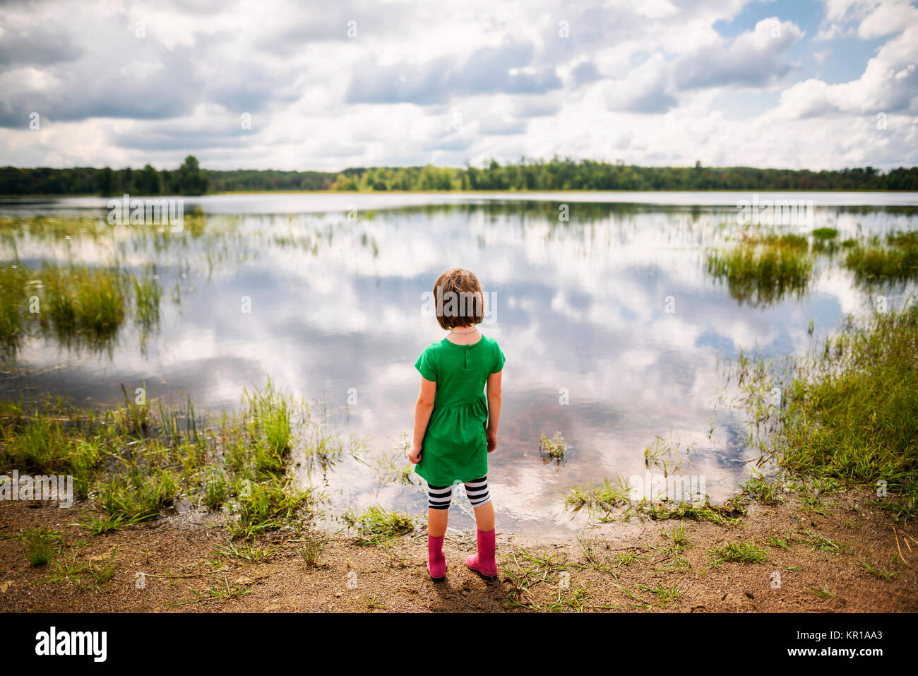 Girl standing at the edge of a lake Stock Photo - Alamy