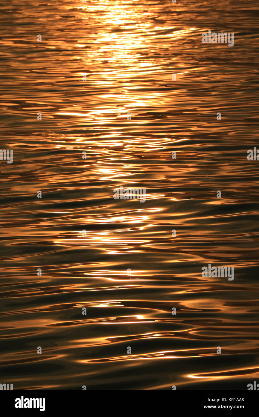 Golden sparkling morning sunlight reflections on the sea water surface ...