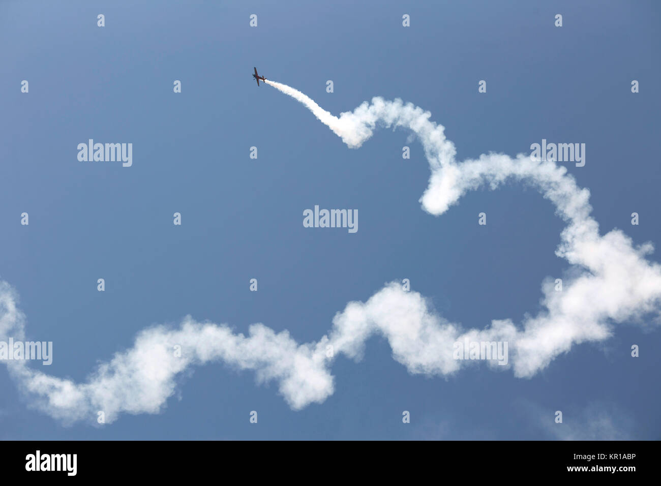Aerobatic plane with a white smoke trail in sky Stock Photo - Alamy