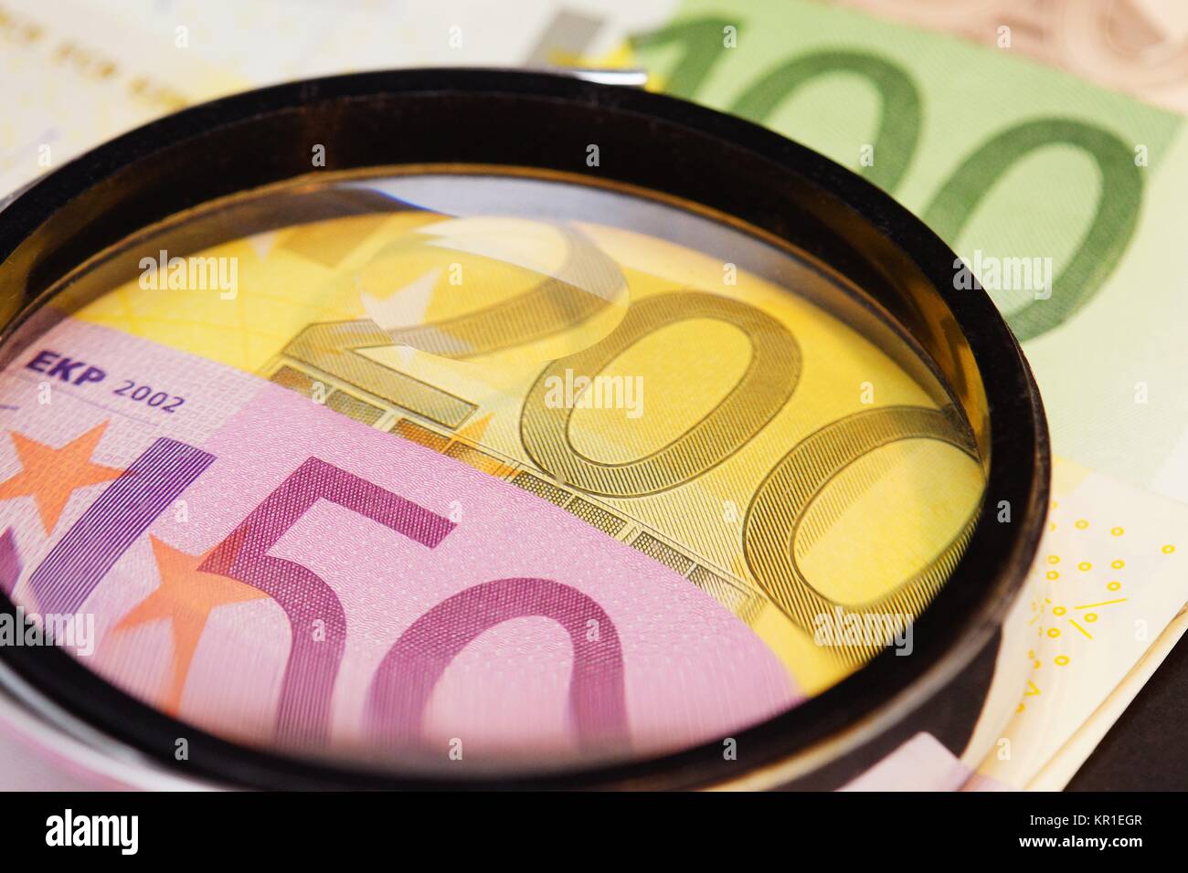 euro banknotes are under a magnifying glass Stock Photo - Alamy