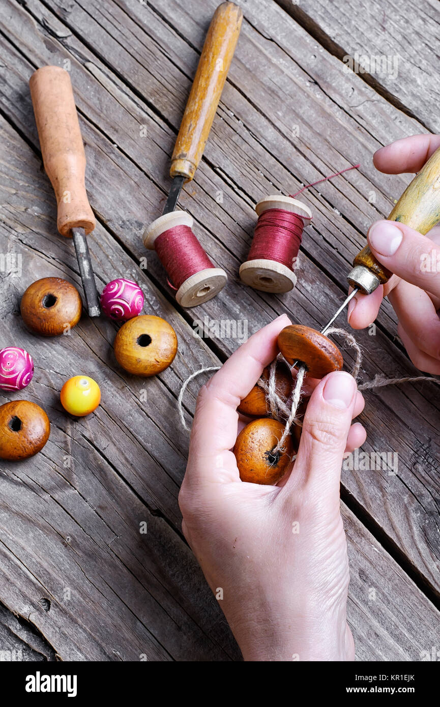 Hands in the process of stringing wooden beads on a rope at work Stock ...