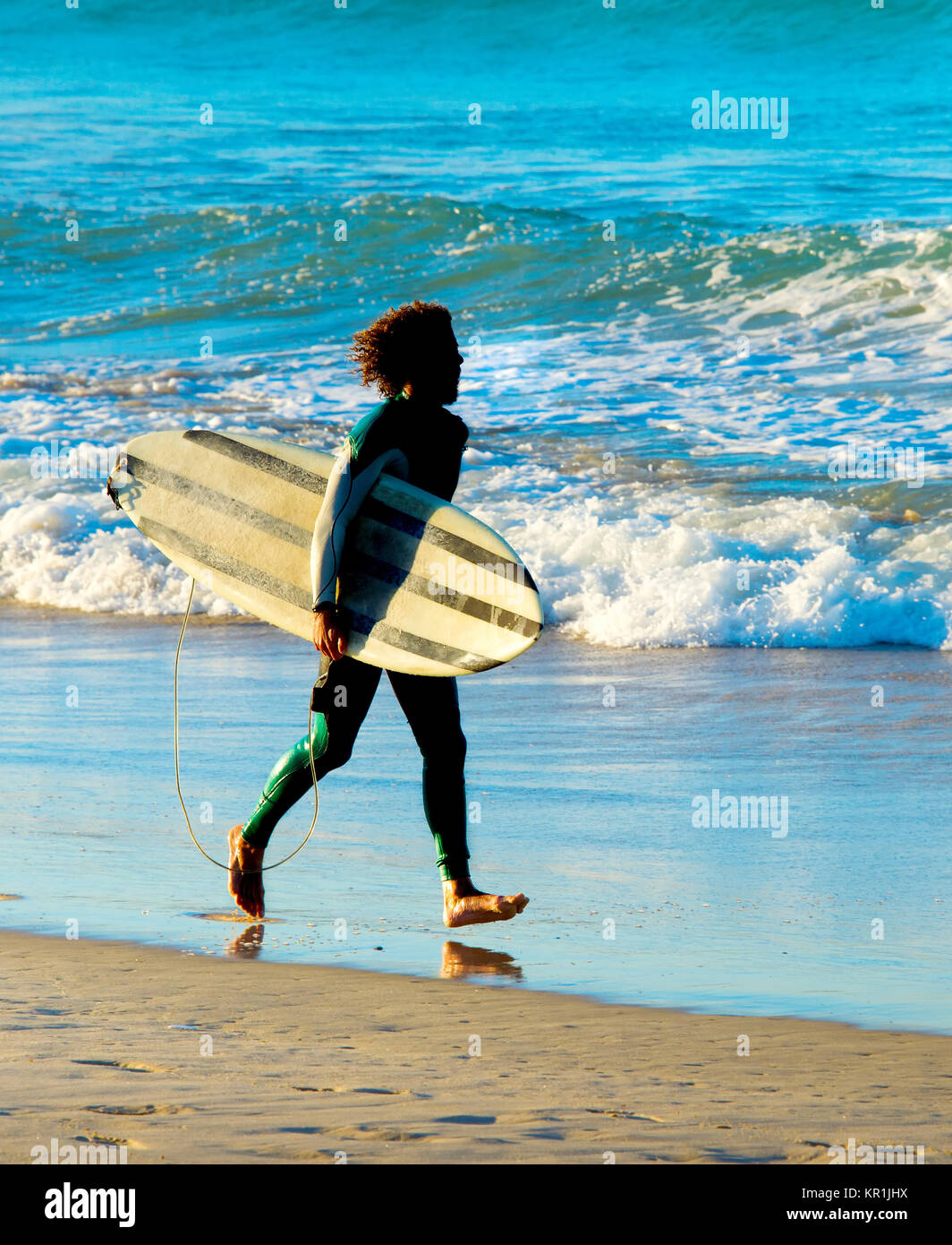 Surfer running with surfboard on the ocean beach at sunset. Portugal ...