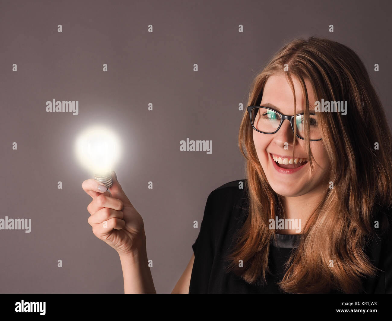 Cheerful female student with a glowing light bulb, great idea concept ...