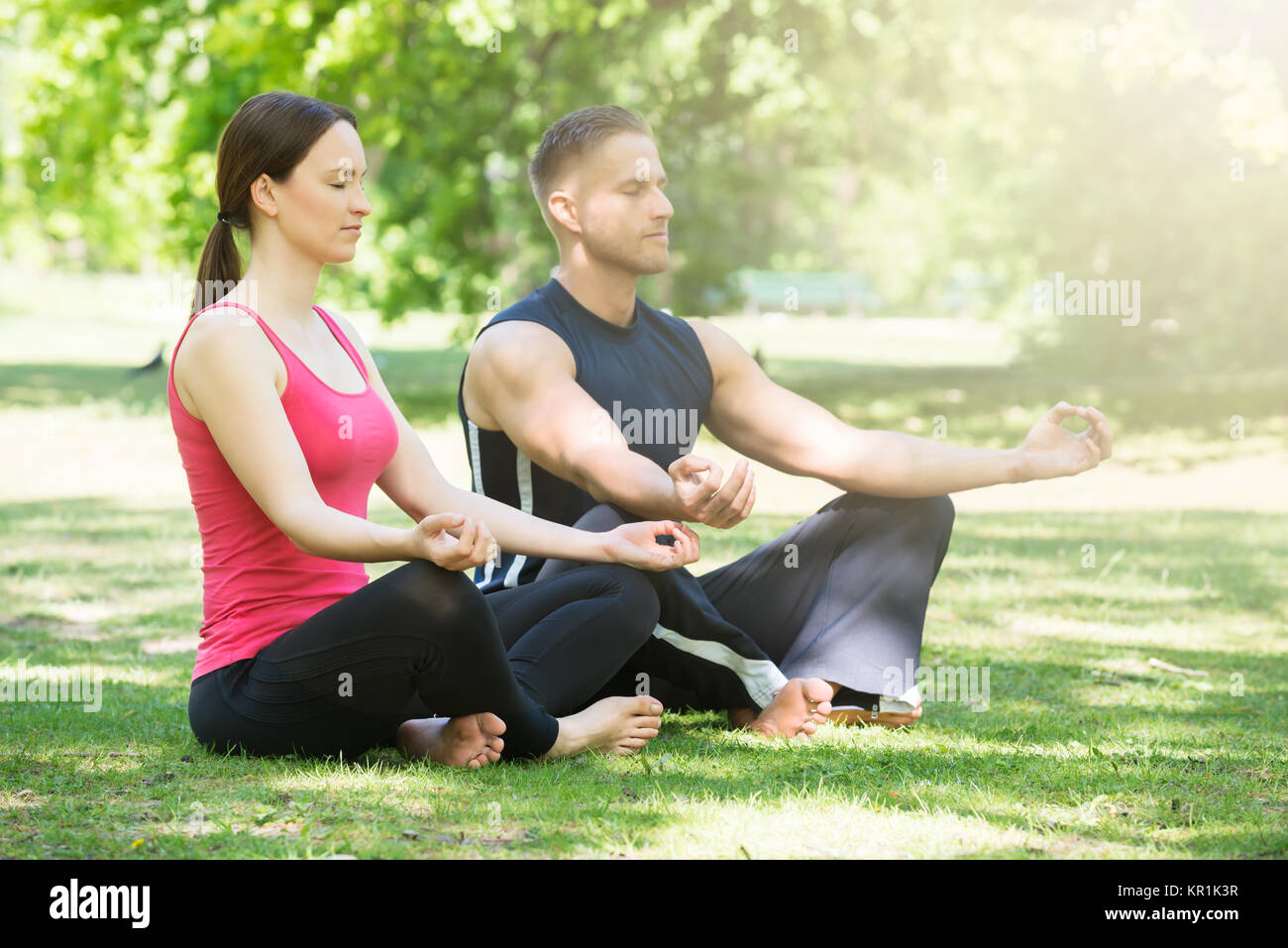 Couple Doing Yoga In Park Stock Photo - Alamy