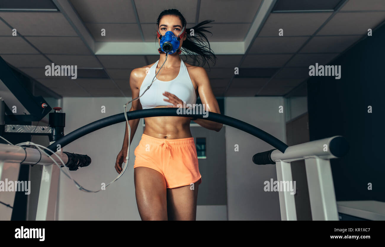 Female athlete with mask running on treadmill to analyze her fitness ...