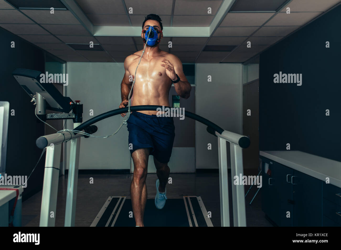 Fit young man running on treadmill with a mask in sports lab. Athlete ...