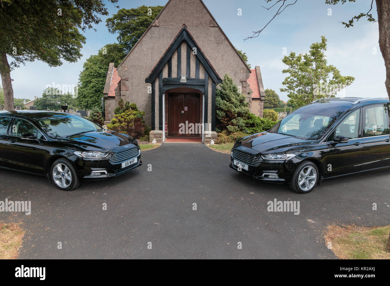 funeral director's hearse and limo outside a small chapel in a cemetery ...