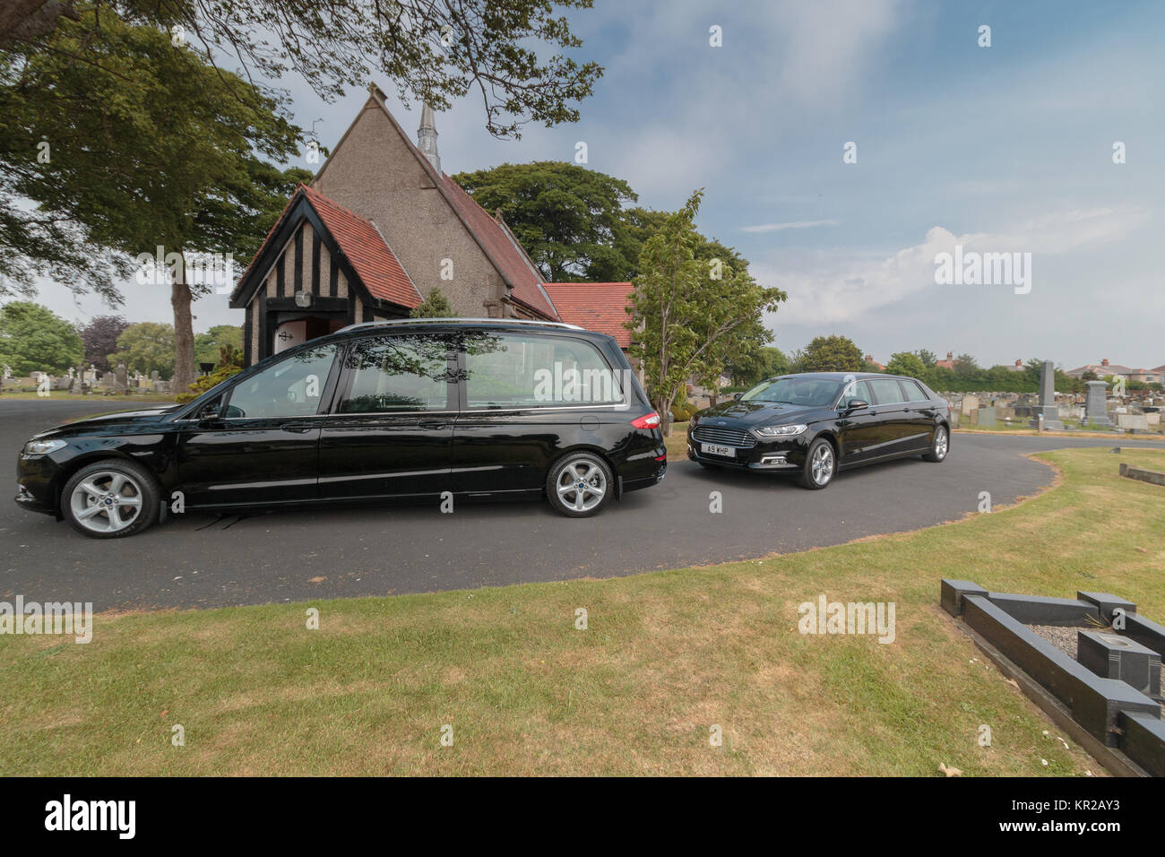 funeral director's hearse and limo outside a small chapel in a cemetery ...