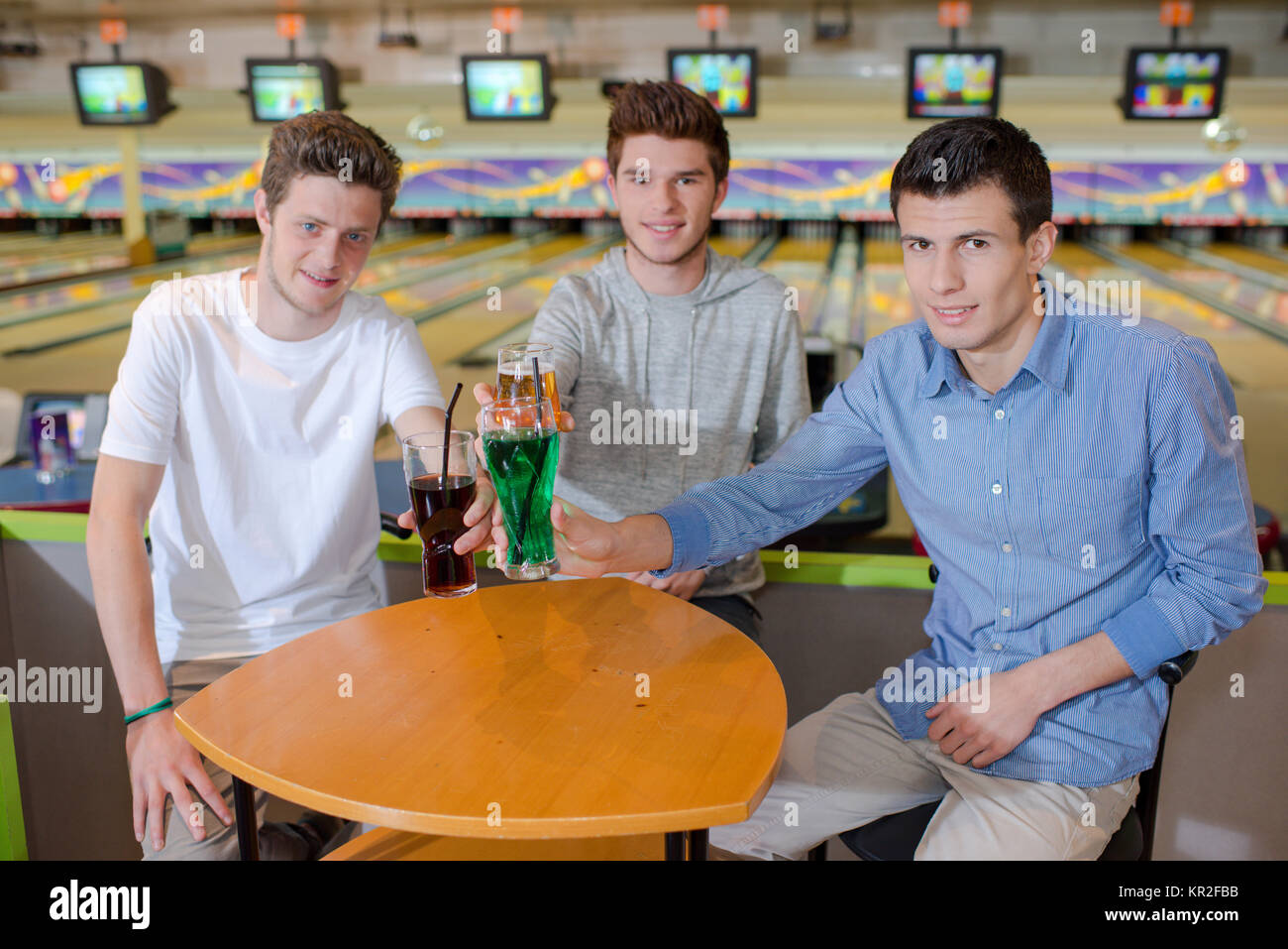 three young men having a drink Stock Photo - Alamy