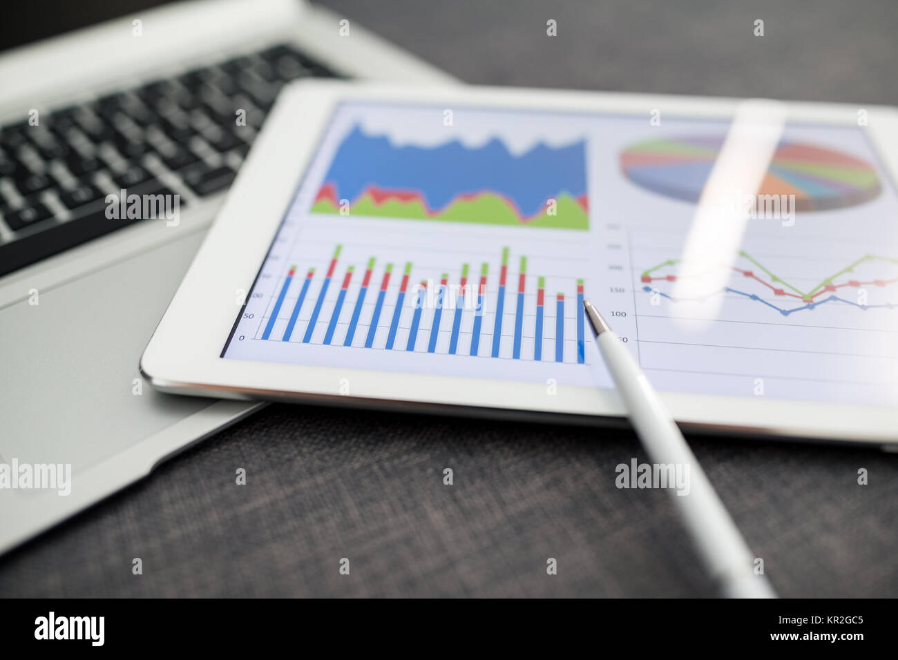 Workplace with tablet pc showing charts Stock Photo - Alamy