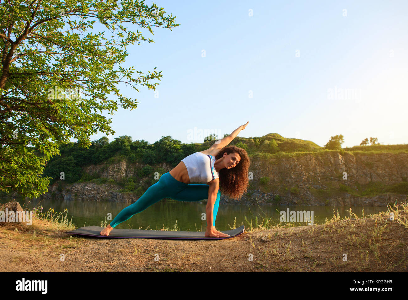 Young woman is practicing yoga near river Stock Photo - Alamy