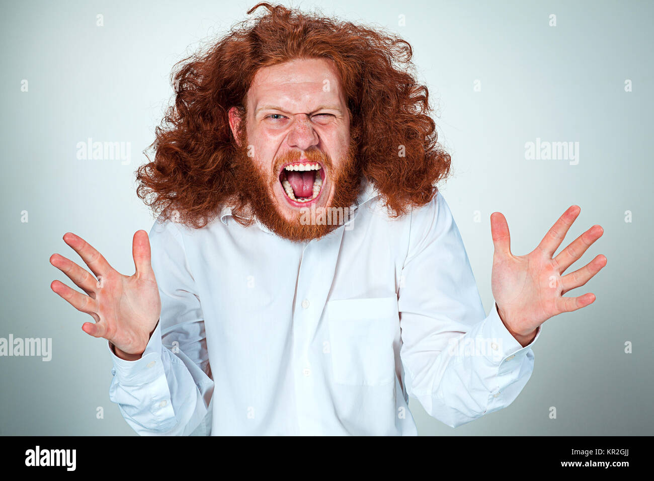 Portrait of screaming young man with long red hair and shocked facial ...