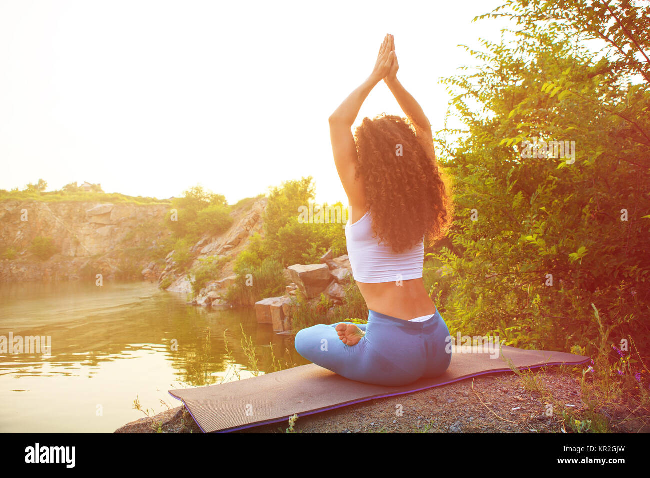 Young woman is practicing yoga near river Stock Photo - Alamy