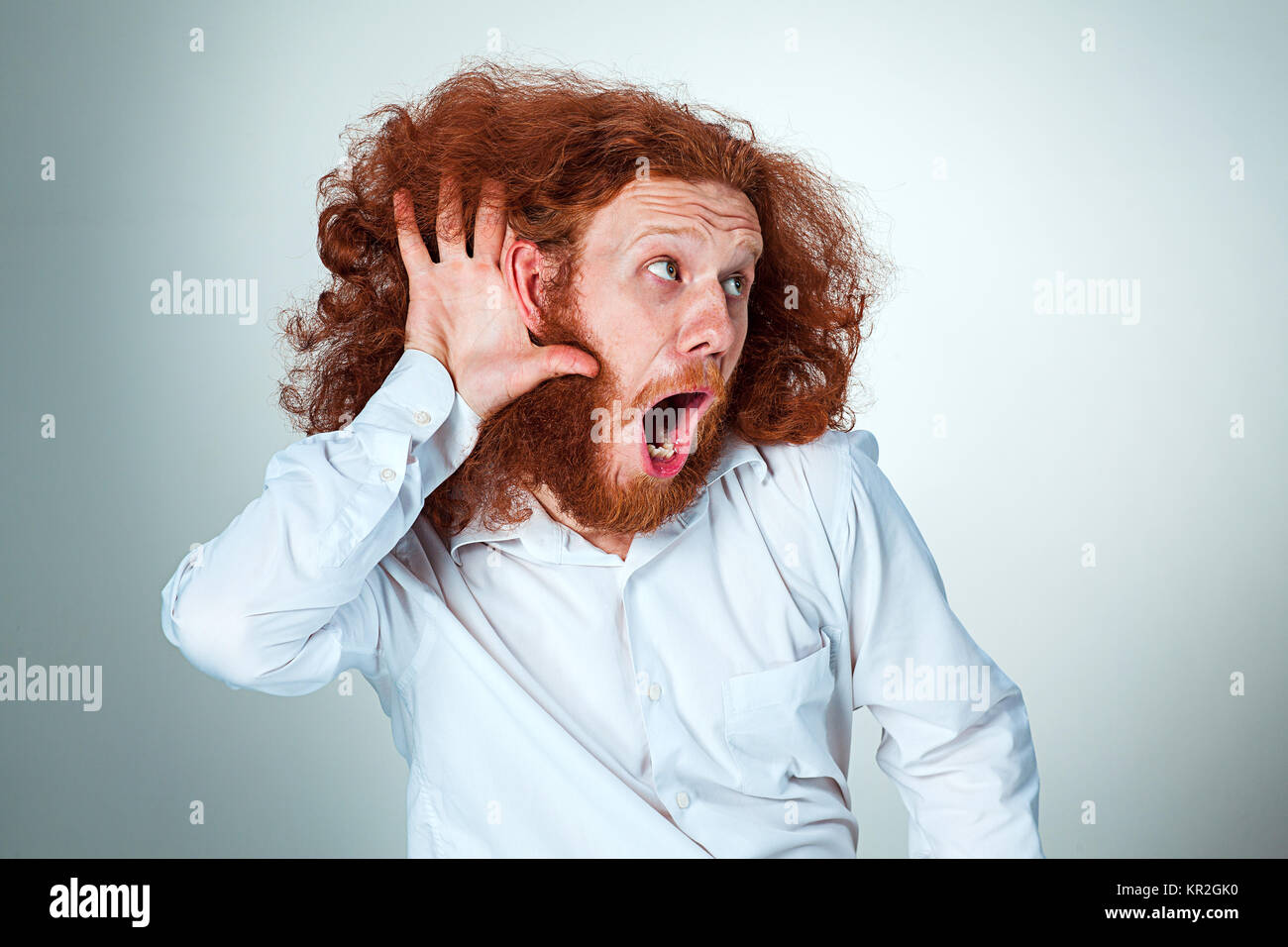 Portrait of screaming young man with long red hair and shocked facial ...