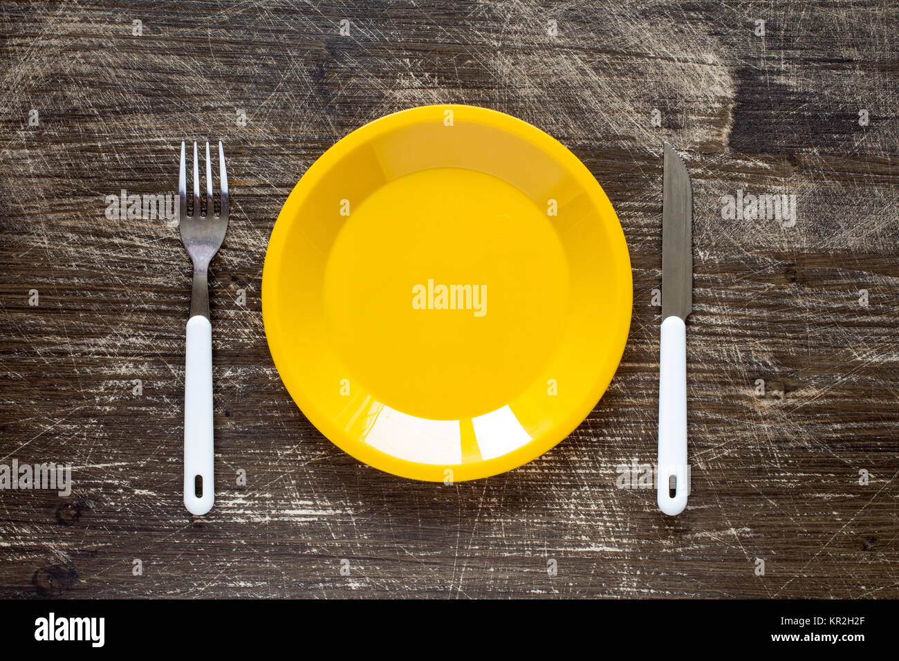 Empty yellow plate, fork and knife Stock Photo - Alamy
