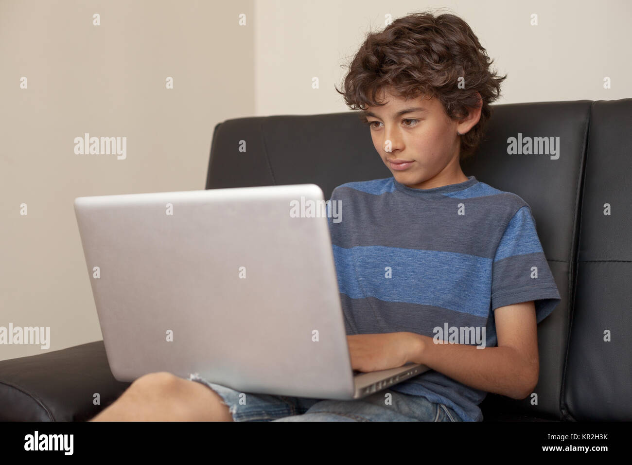 Latino boy sitting on sofa with laptop computer Stock Photo - Alamy