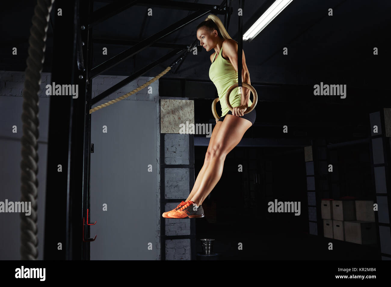 Low angle shot of a sportswoman doing ring dips at the crossfit gym ...