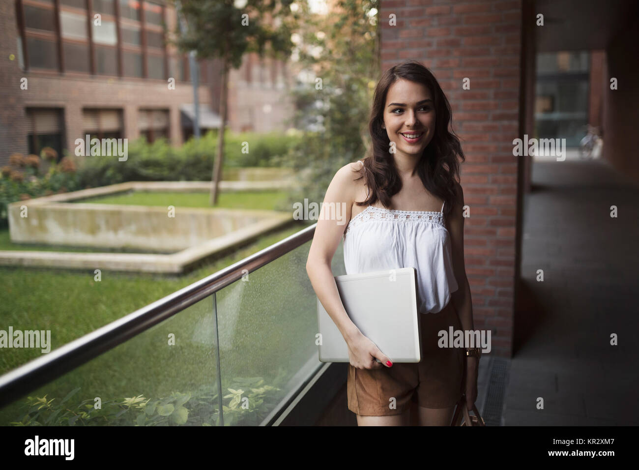 Portrait of young smiling woman holding laptop Stock Photo - Alamy