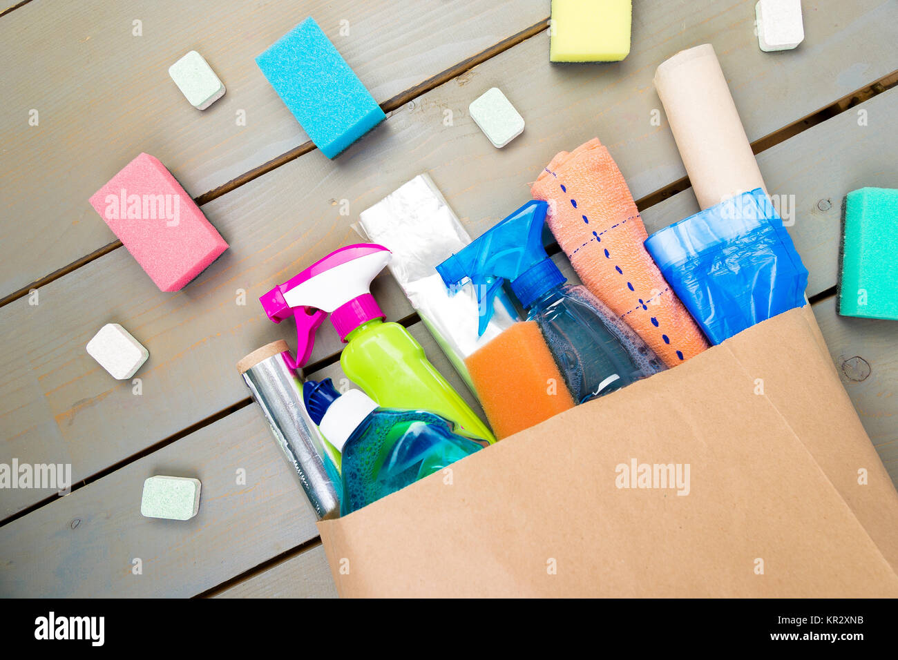 Full paper bag of different house cleaning product on wooden table ...