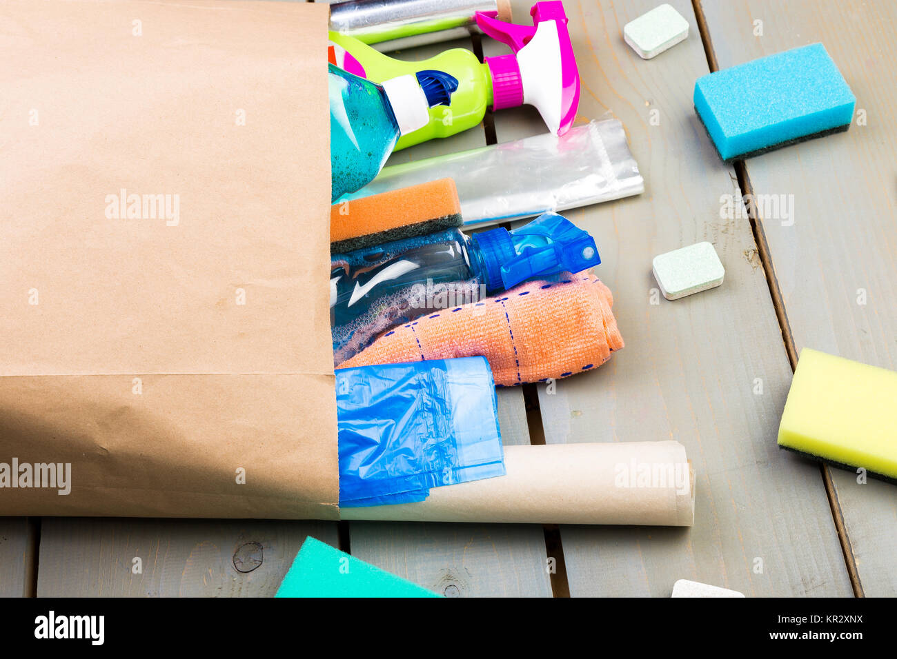 Full paper bag of different house cleaning product on wooden table ...