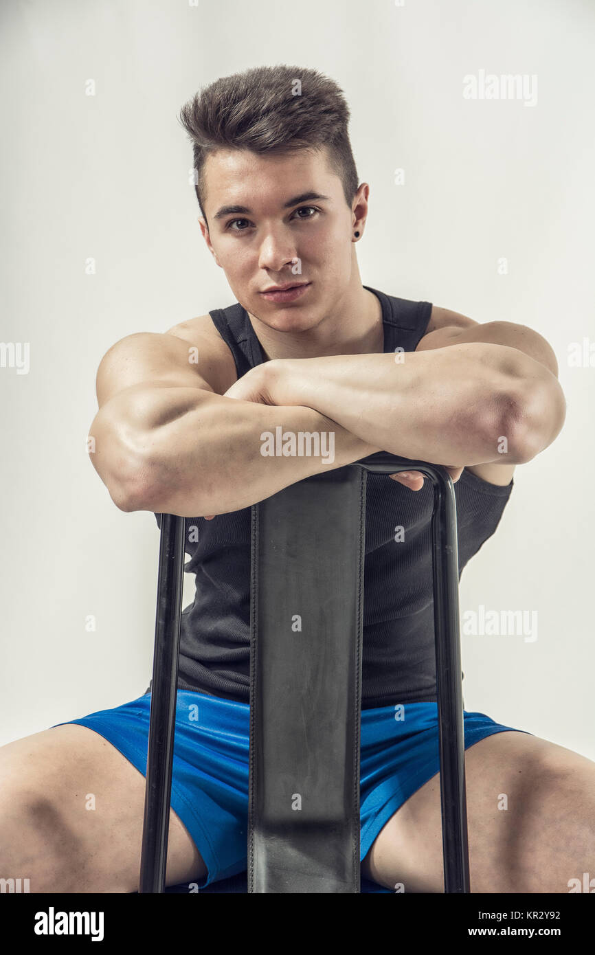 Handsome young muscular man sitting on chair Stock Photo - Alamy