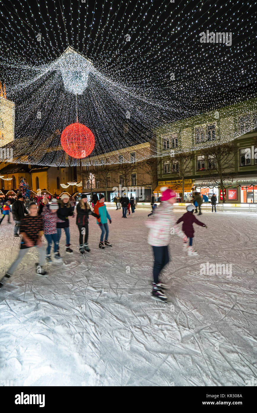 people skating on the ice rink in a town square in the center of ...