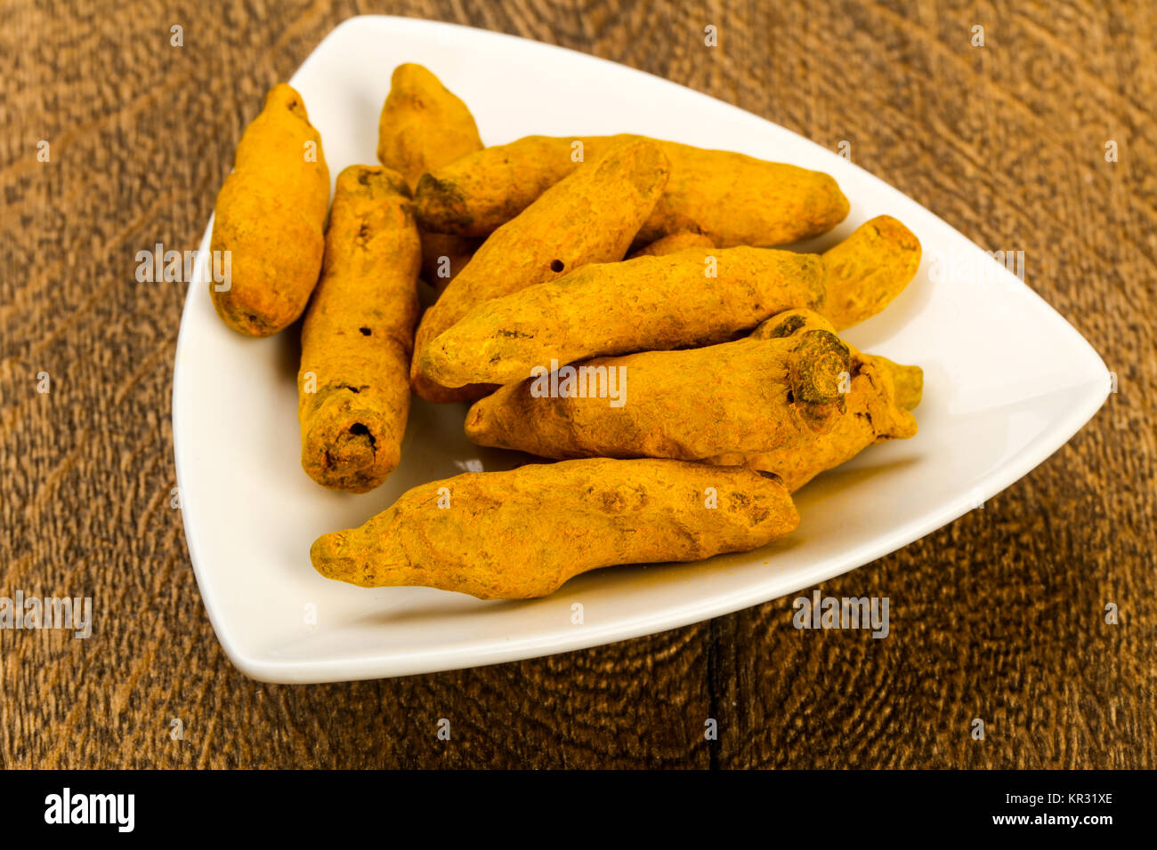 Tumeric roots heap in the bowl over wooden background Stock Photo - Alamy