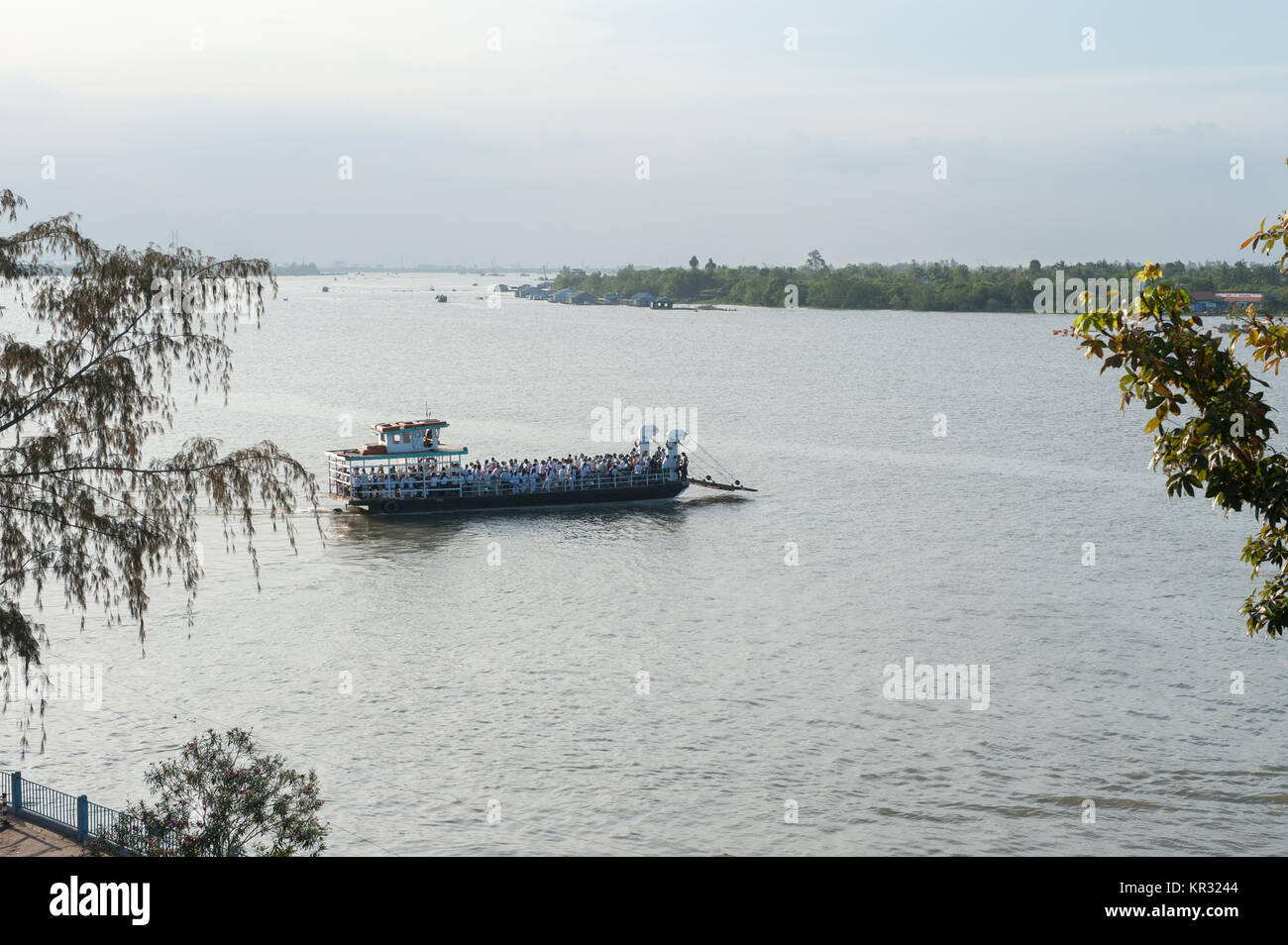 Ferry carrying school children in white uniforms across the Mekong ...
