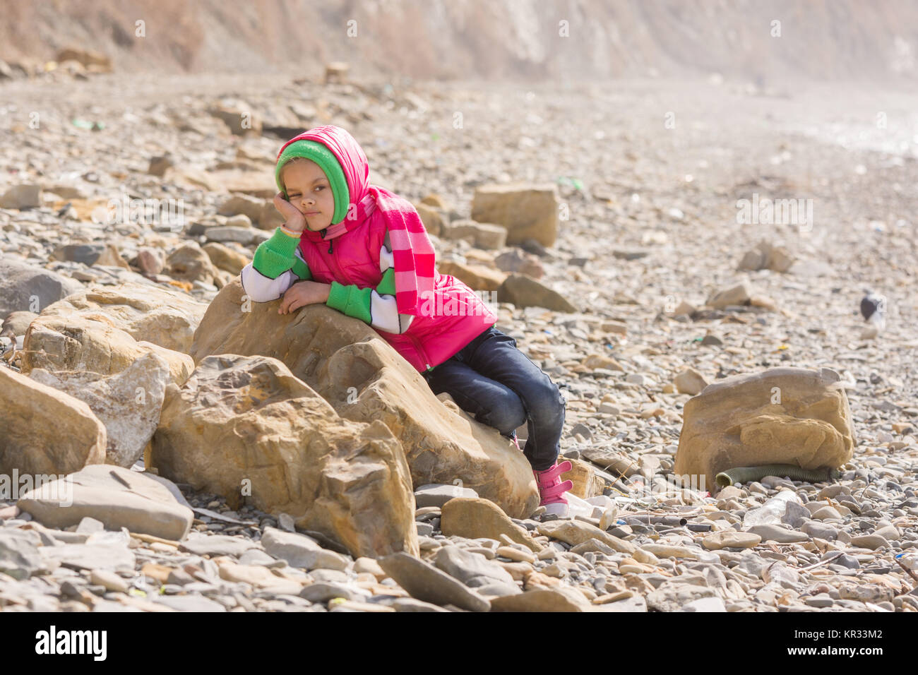 A bored tired girl lay down on a big rock by the sea Stock Photo - Alamy