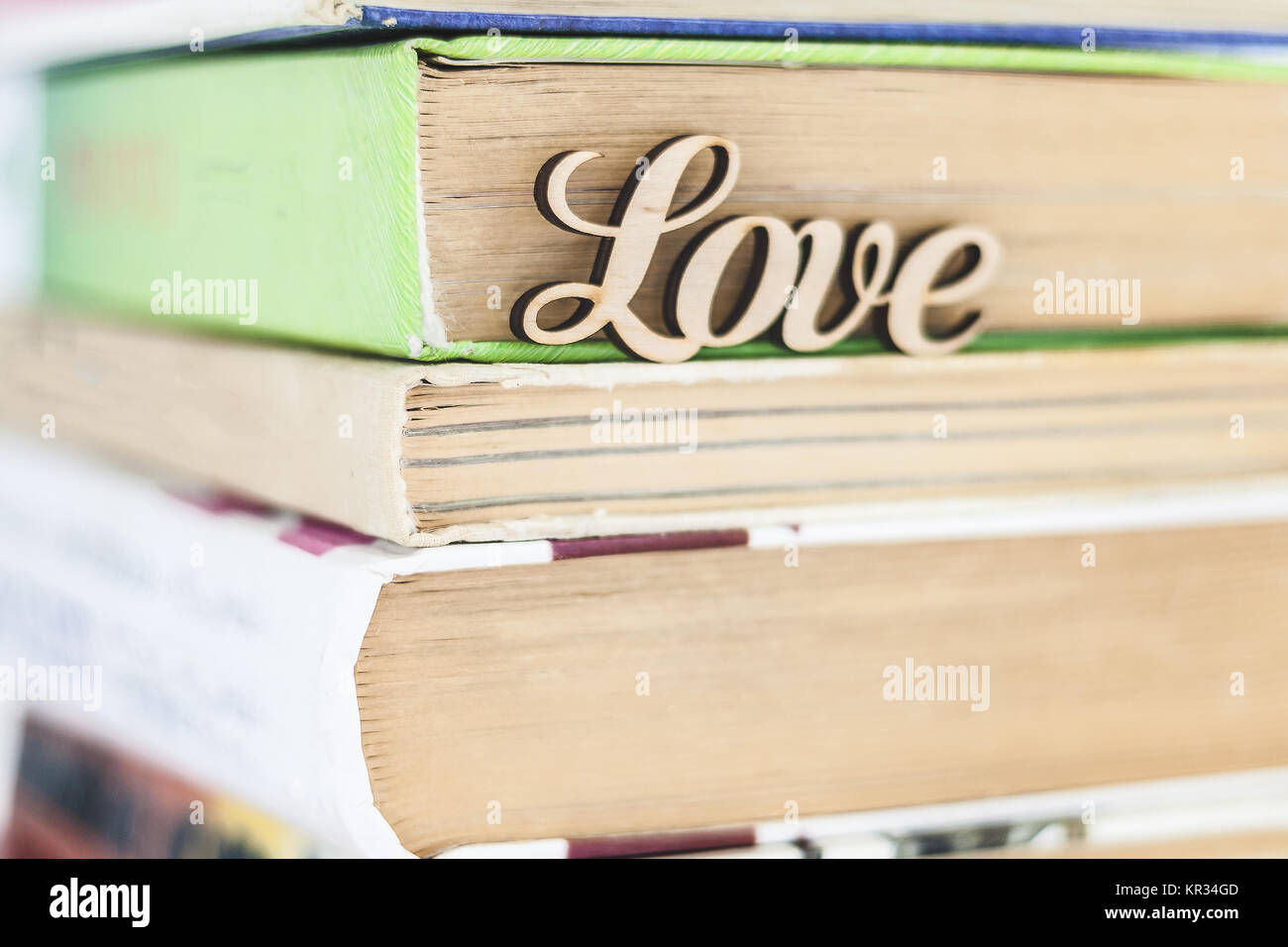 on a stack of old books wooden word love Stock Photo - Alamy