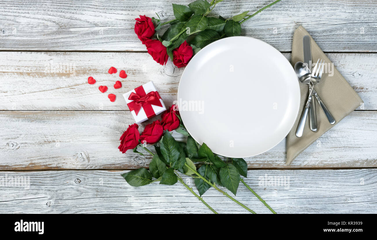 Valentine dinner setting with gift, red roses and heart shapes on ...