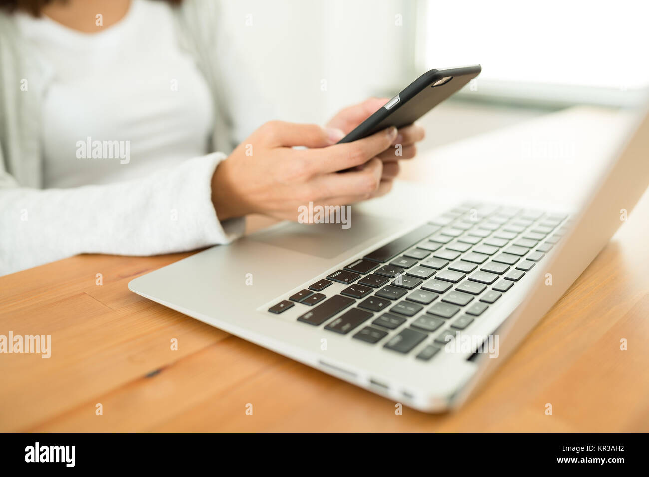 Woman using mobile phne with her laptop computer Stock Photo - Alamy