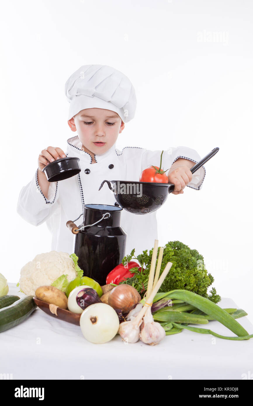 One little boy as chef cook making salad, cooking with vegetables ...